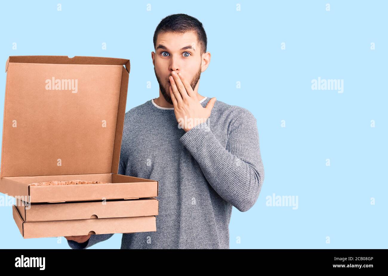 Young handsome man holding delivery italian pizza boxes covering mouth ...