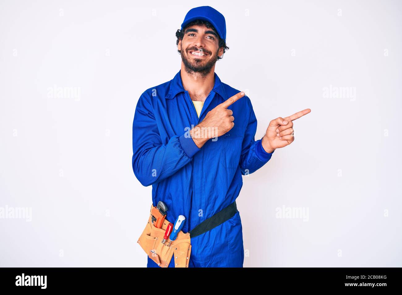 Handsome young man with curly hair and bear weaing handyman uniform ...