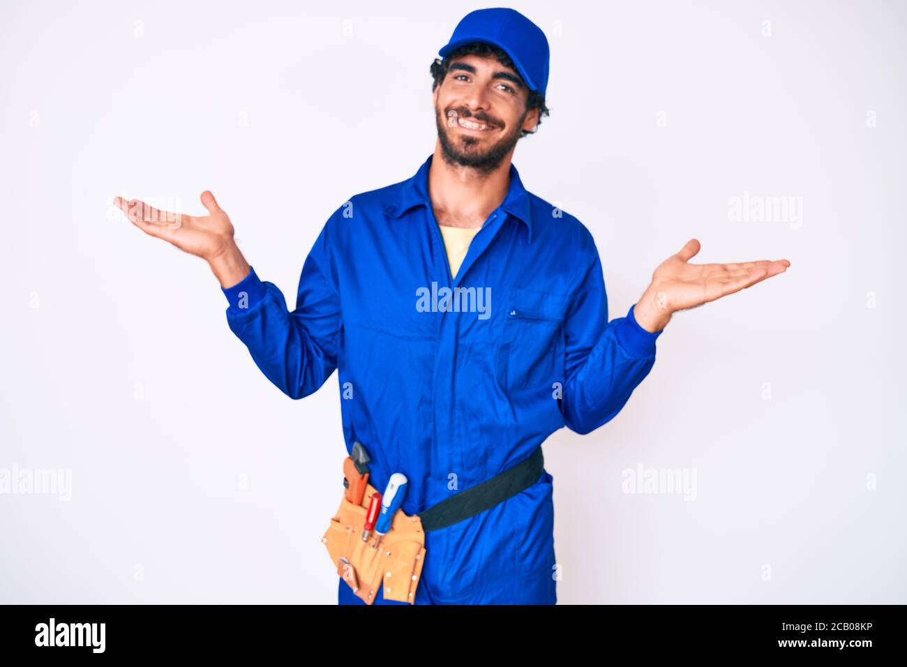 Handsome young man with curly hair and bear weaing handyman uniform ...