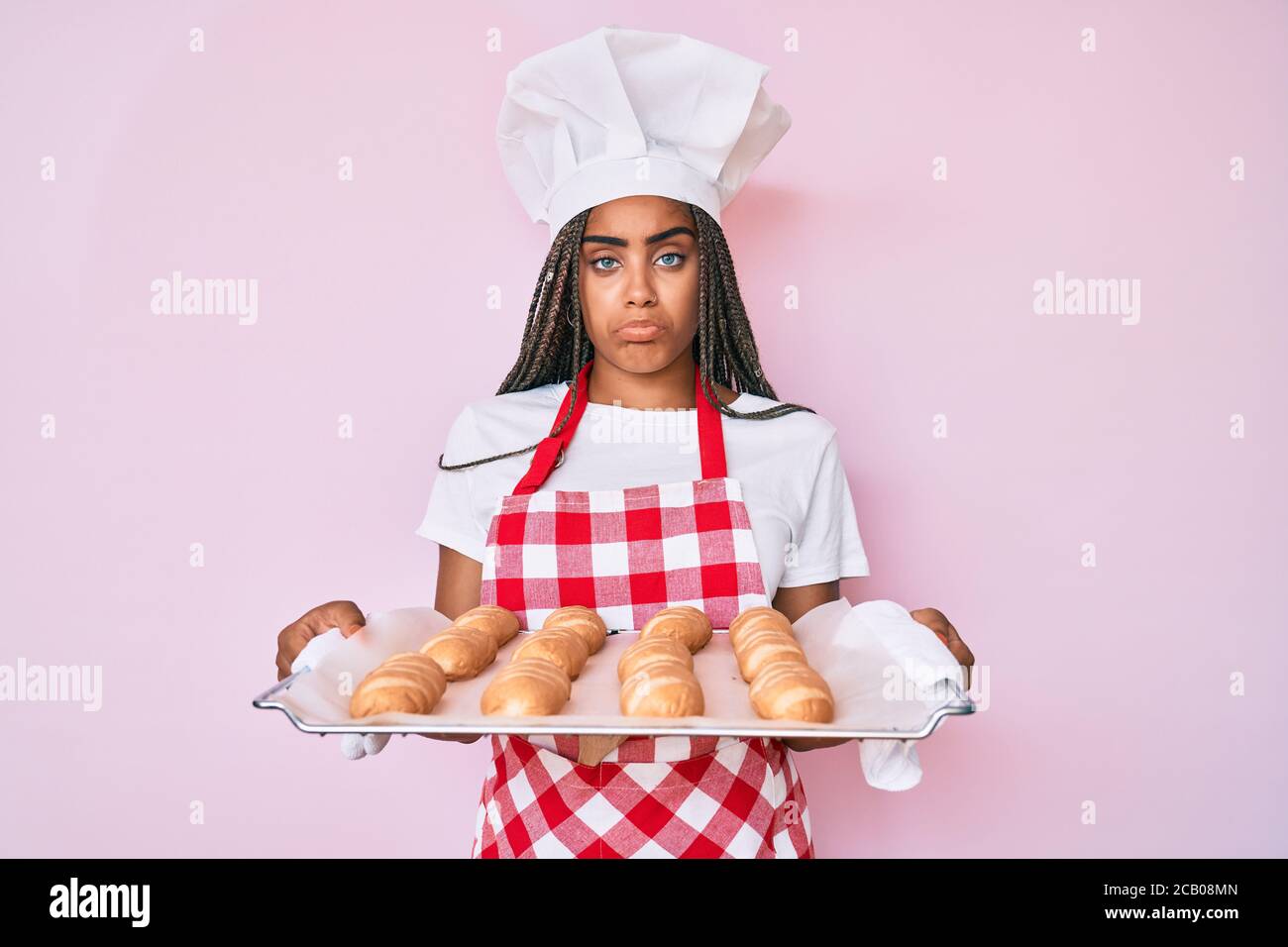 Young african american woman with braids wearing baker uniform holding ...