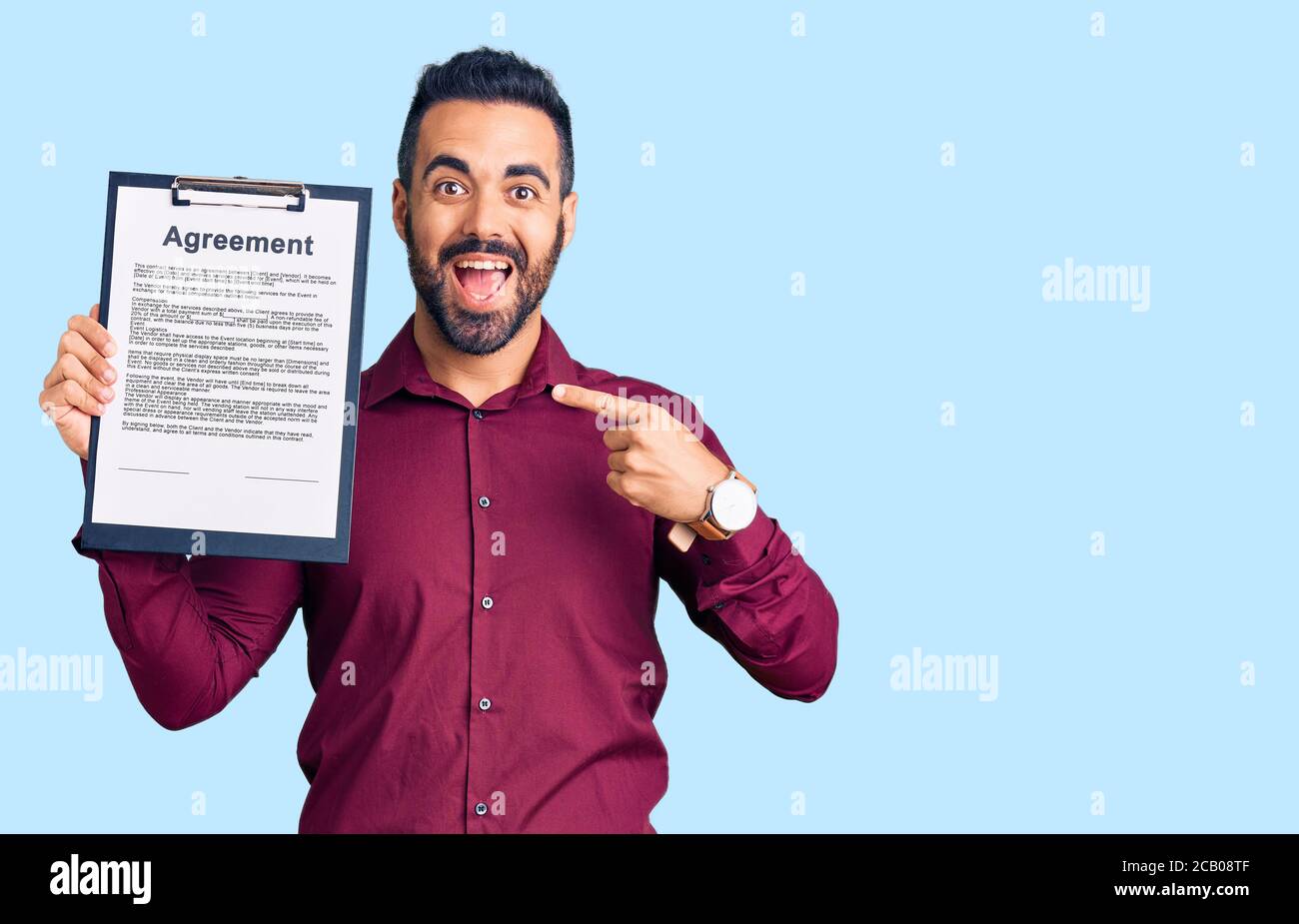 Young Hispanic Man Holding Clipboard With Agreement Document Smiling