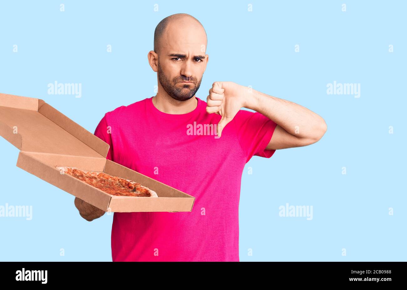 Young handsome man holding delivery pizza cardboard box with angry face ...