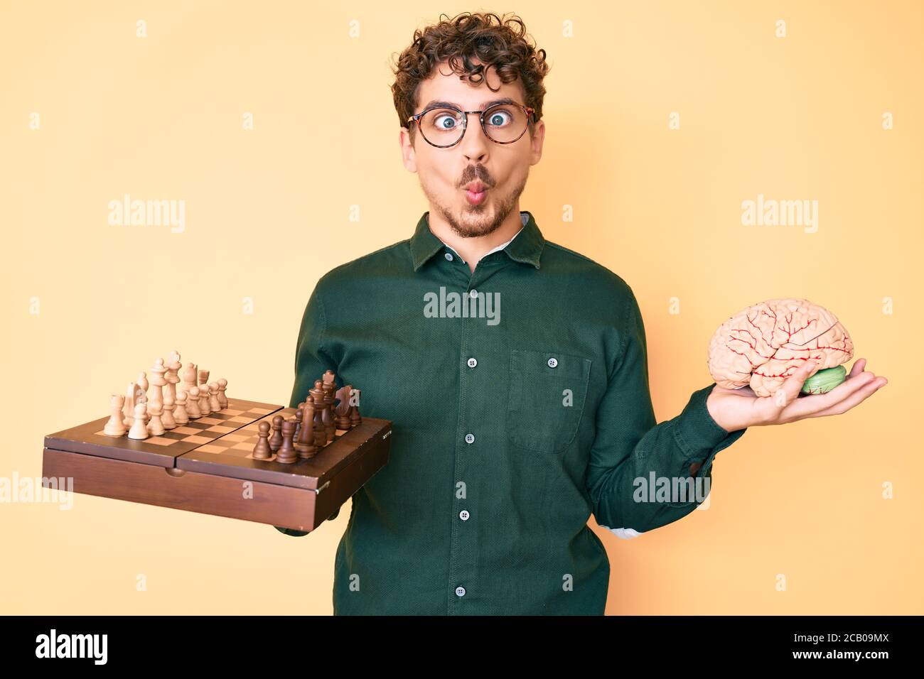 Young caucasian man with curly hair holding brain while playing chess ...