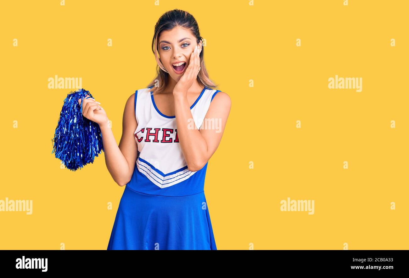 Young beautiful woman wearing cheerleader uniform afraid and shocked ...