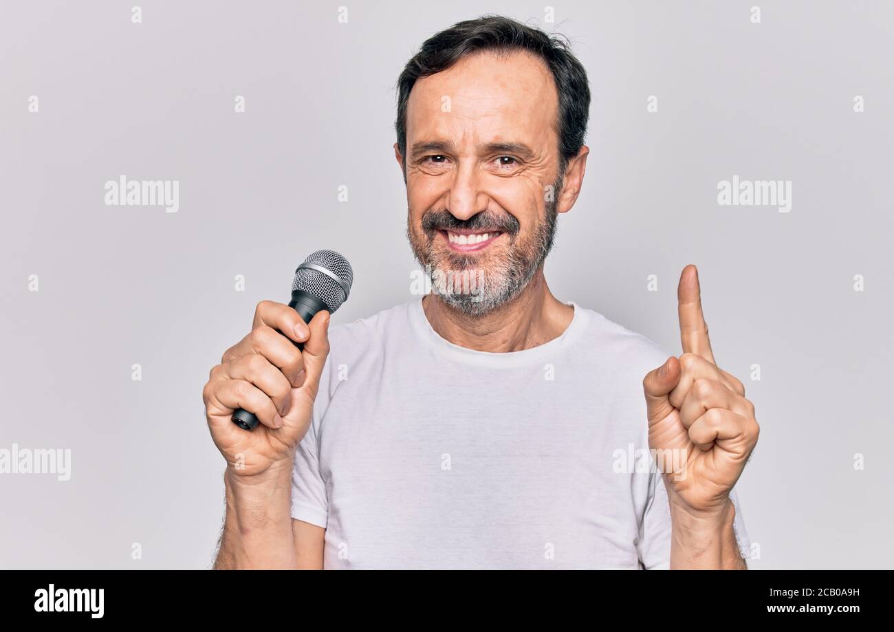 Middle age handsome singer man singing using microphone over isolated ...
