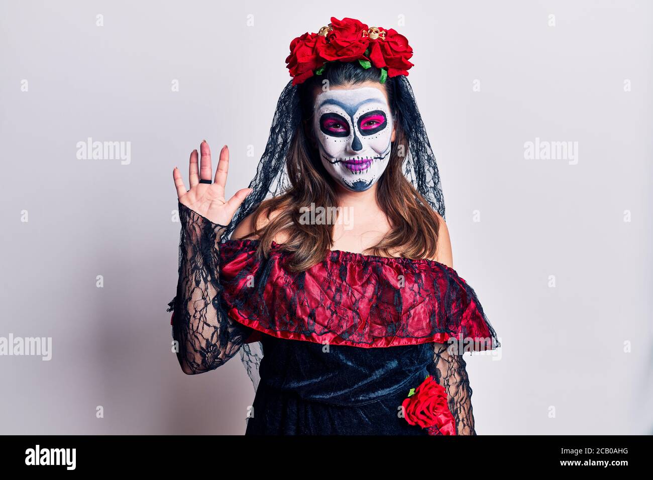 Young woman wearing day of the dead costume over white waiving saying ...