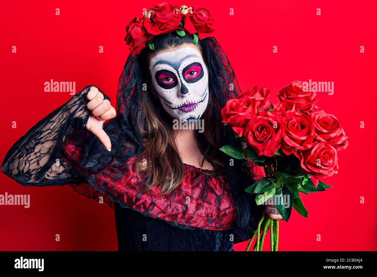 Young woman wearing day of the dead costume holding flowers with angry ...