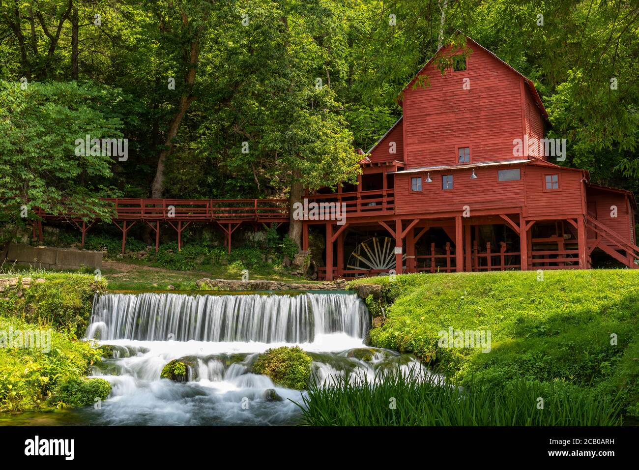 An old red grist mill with a small waterfall Stock Photo - Alamy