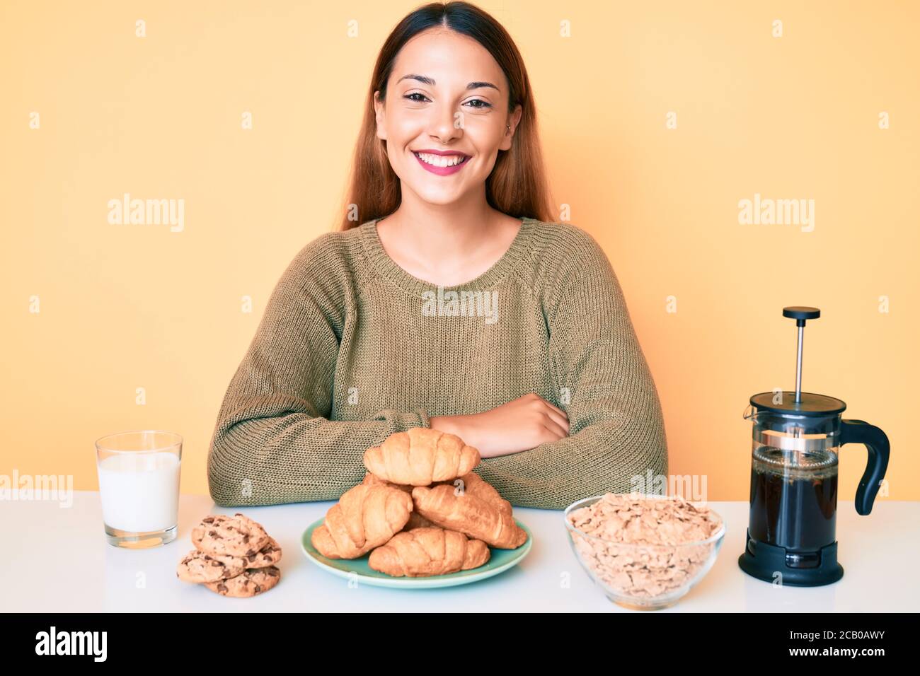 Young brunette woman sitting on the table having breakfast looking ...
