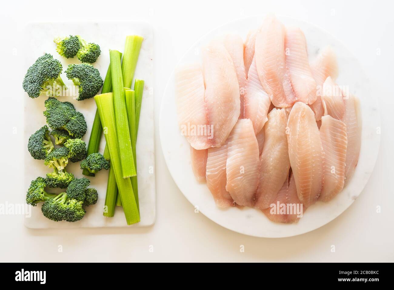 White fish fillet and fresh vegetables. Raw tilapia fish fillet ...