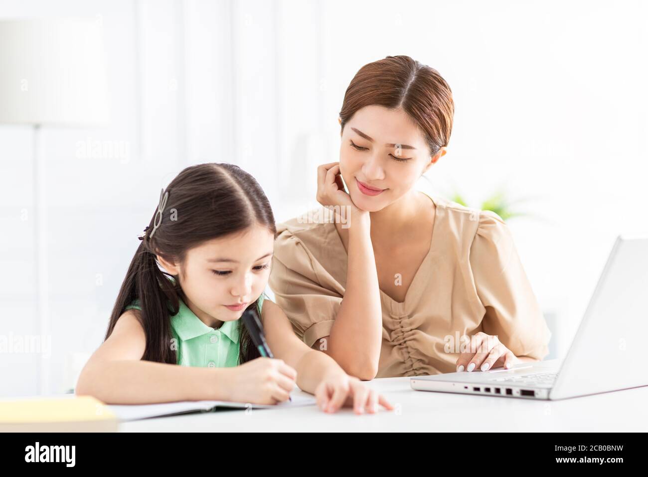 Mother is working and taking care of her daughter at home Stock Photo ...