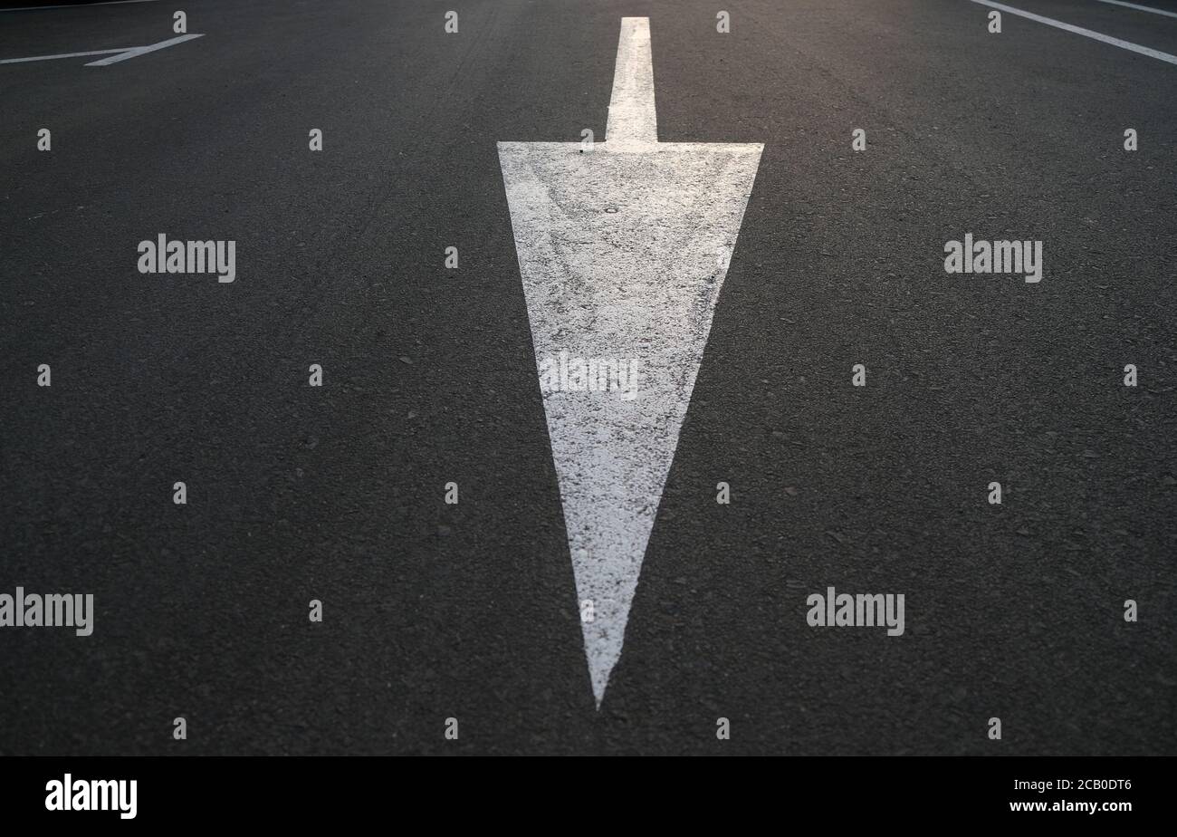 Long white arrow pointing down on black background, angled perspective ...