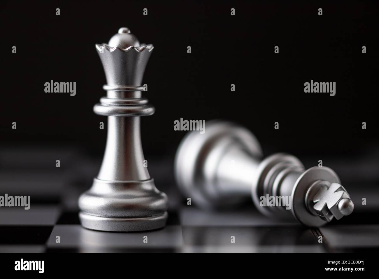 Silver queen standing and king falling in game on the chessboard Stock ...