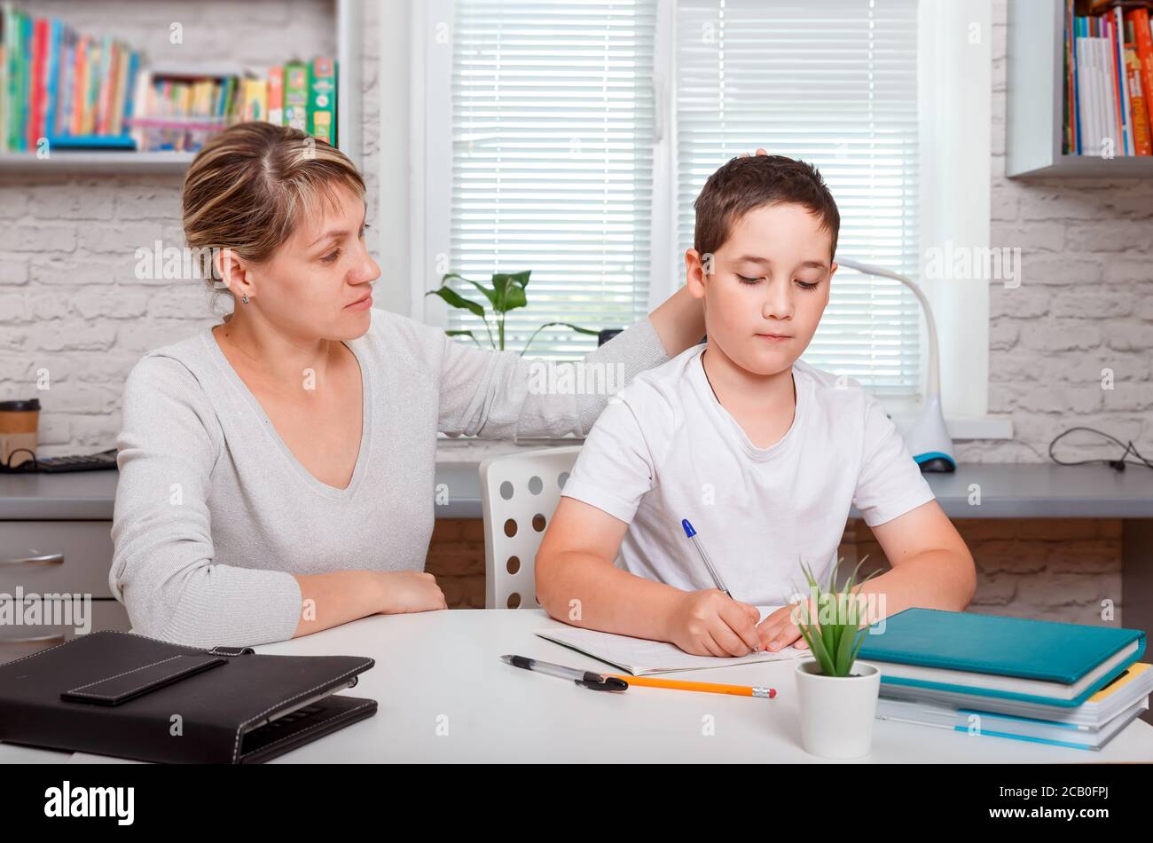 The tutor is engaged with the child, teaches to write and count Stock ...