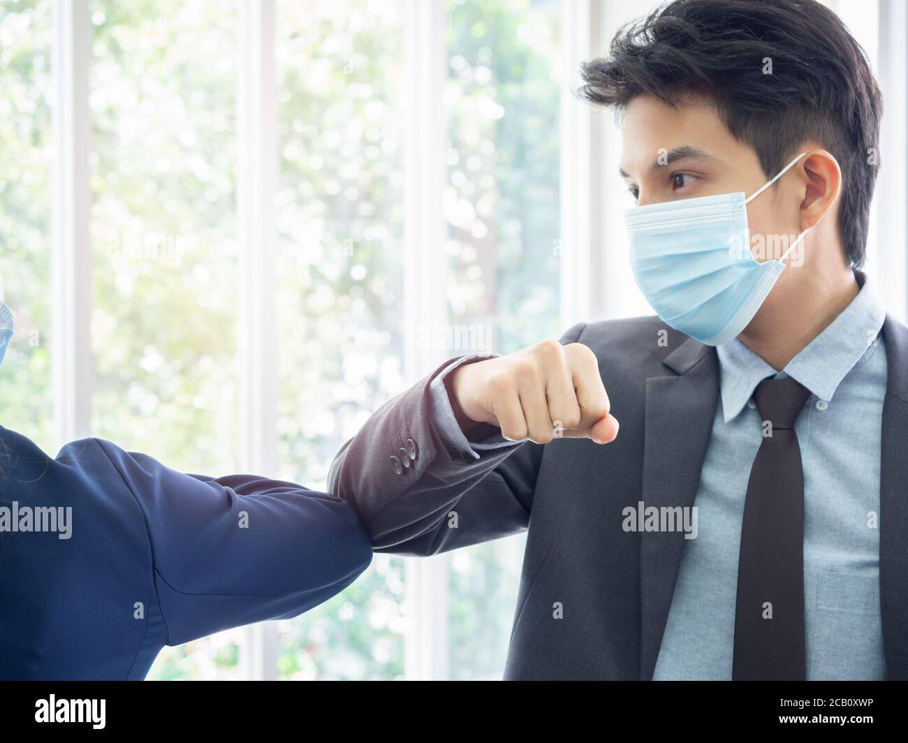Elbow bump. Businessman wearing protective face mask and use elbow to ...