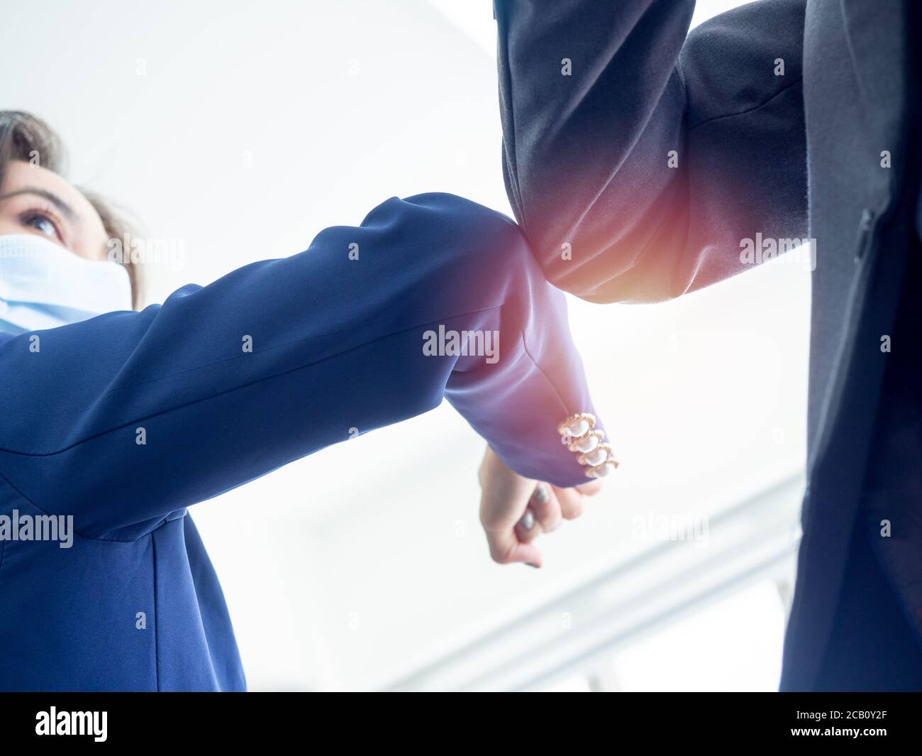 Elbow bump. Business woman wearing medical face mask and use elbow to ...