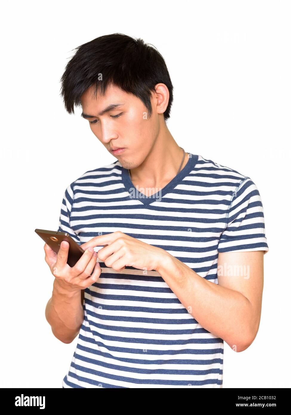 Studio shot of young handsome Asian man using phone isolated against ...