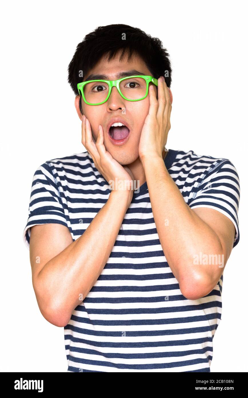 Studio shot of young Asian nerd man looking shocked and surprised ...