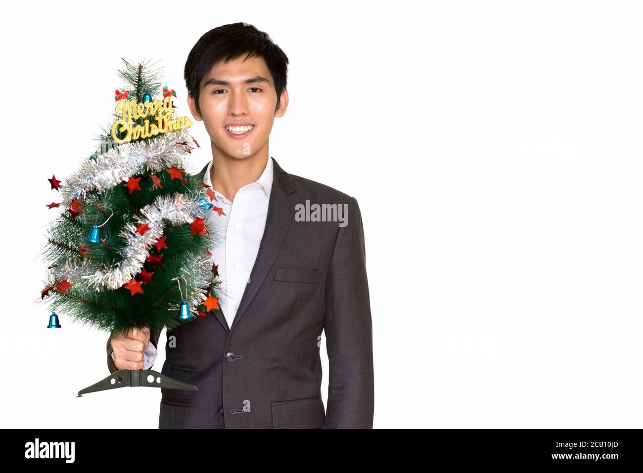 Studio shot of young happy Asian businessman holding Merry Christmas ...
