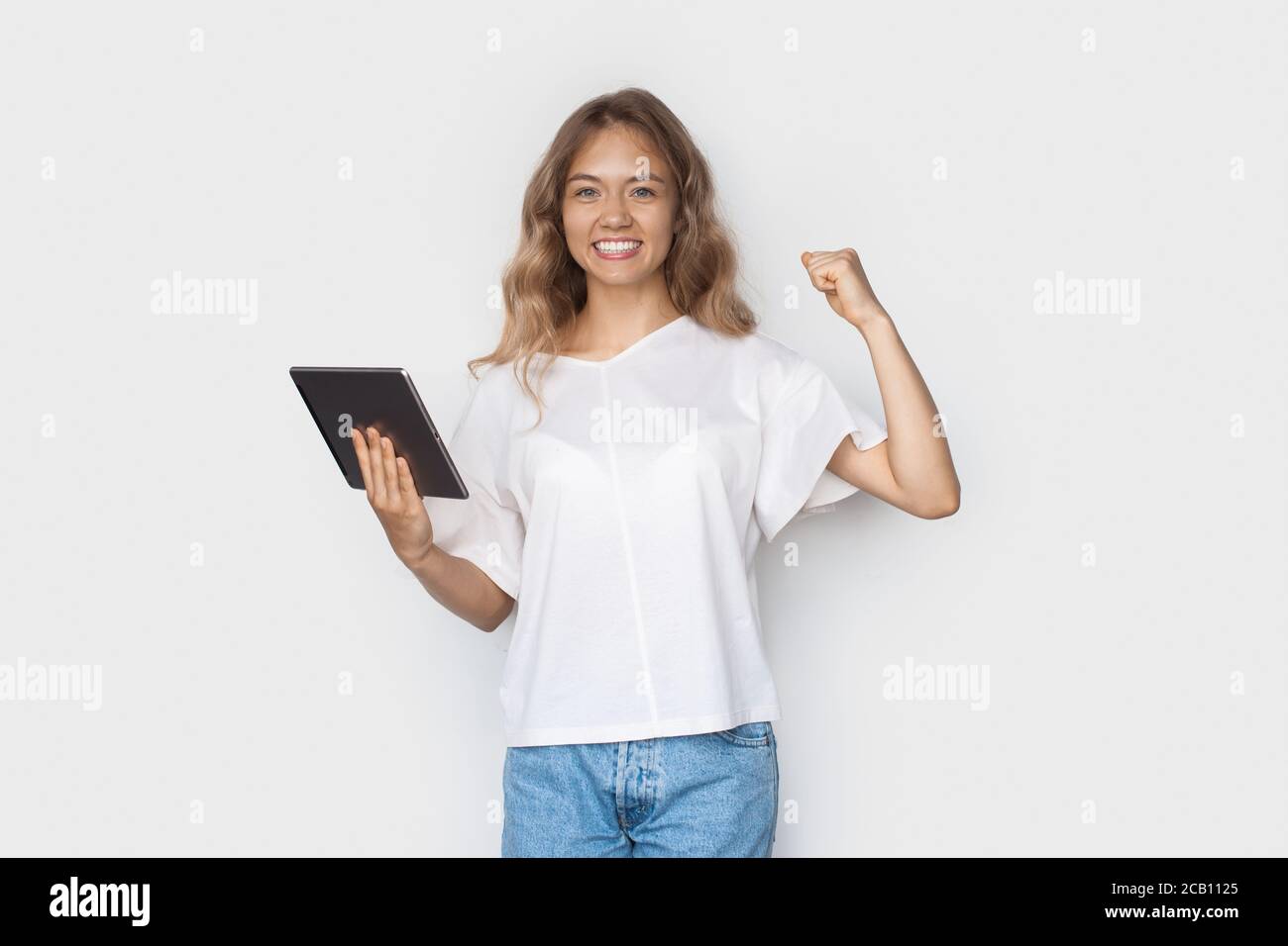 Blonde caucasian woman smiling toothily on a white studio wall ...