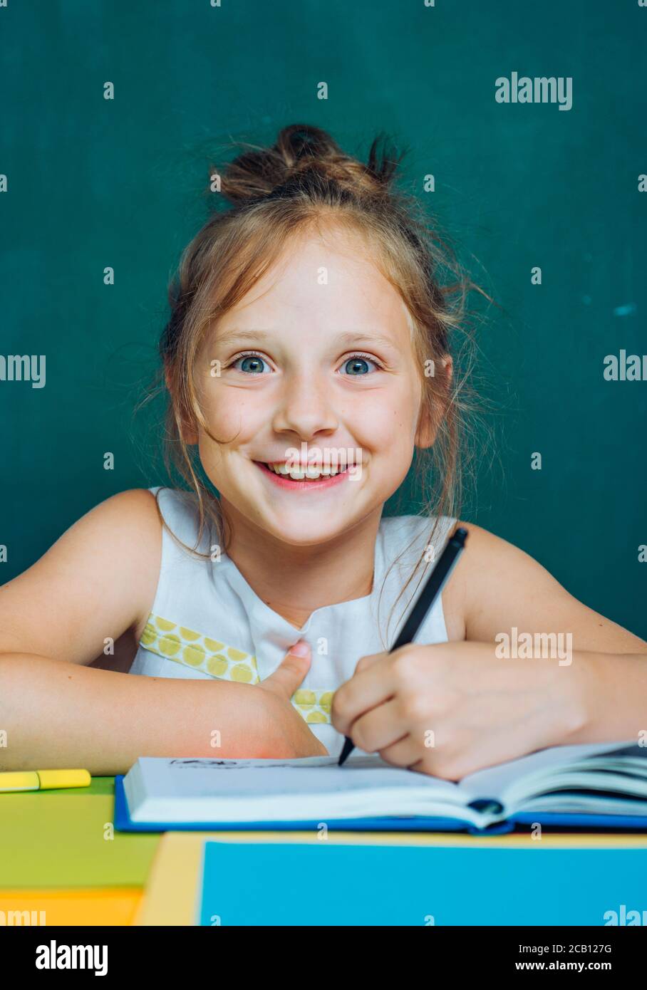 Child is learning in class on background of blackboard. Happy school ...