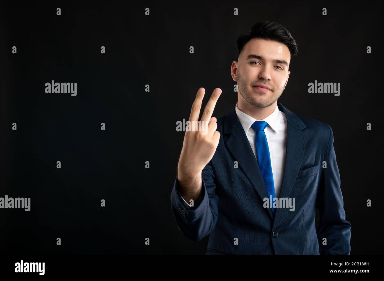 Portrait of business man wearing blue business suit and tie showing two ...