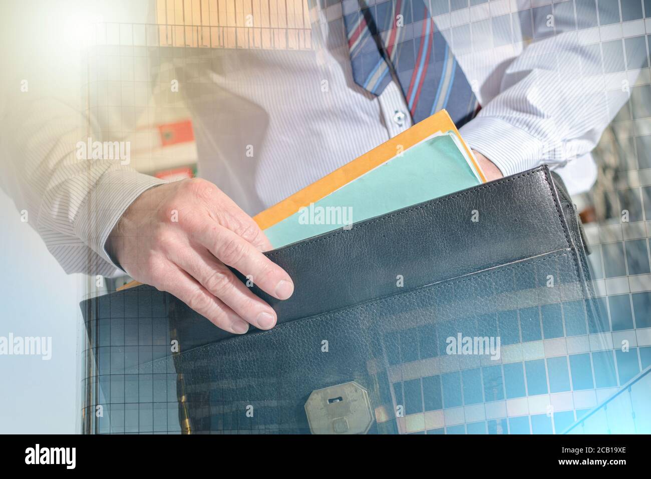 Businessman pulling out folders from his briefcase at office; multiple ...