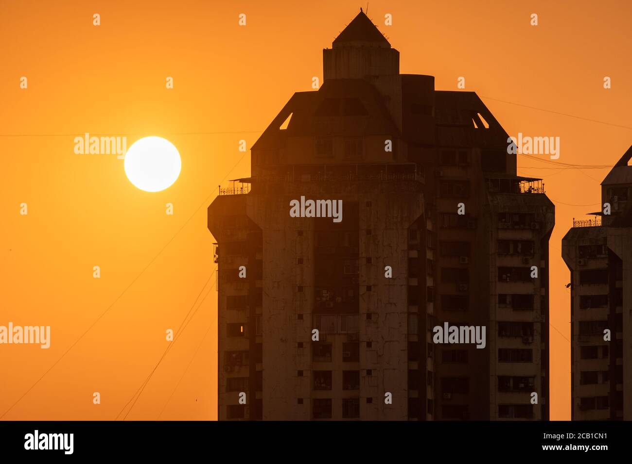 Beautiful view of the sun setting next to a high rise apartment complex ...
