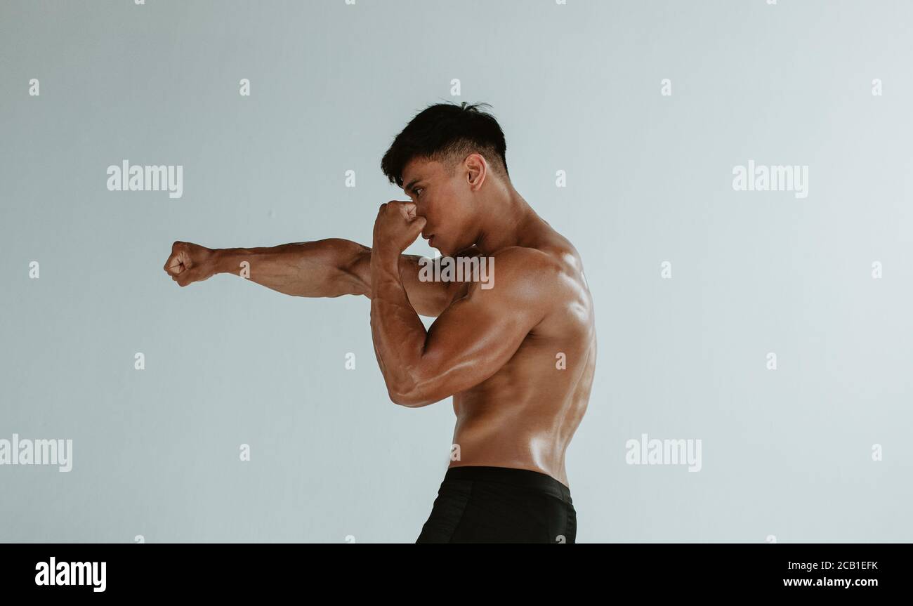 Side view of a muscular sports man training boxing moves in studio ...