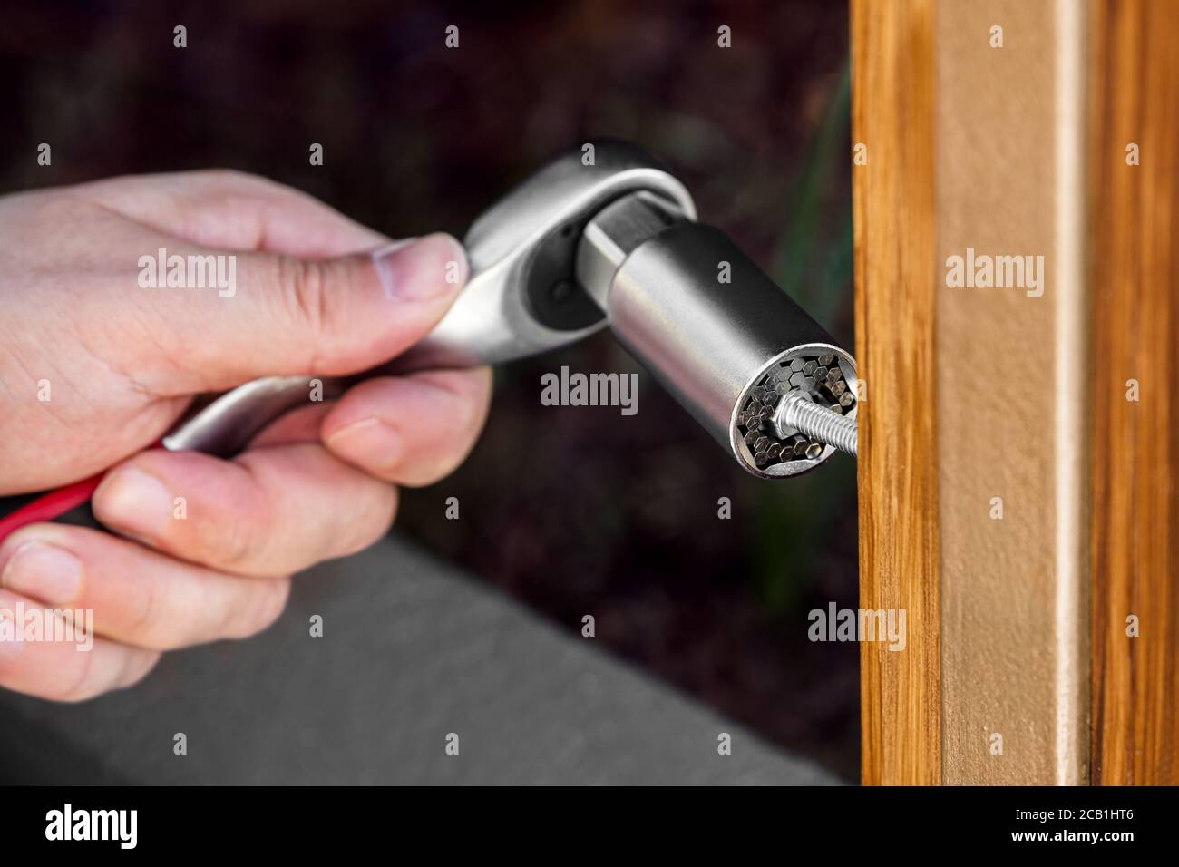 male hand is using a universal adjustable socket wrench to tighten a ...