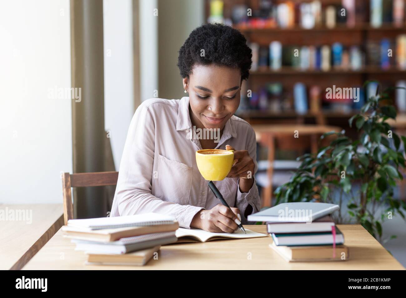 Pretty black girl taking notes during her studies at coffee shop Stock ...