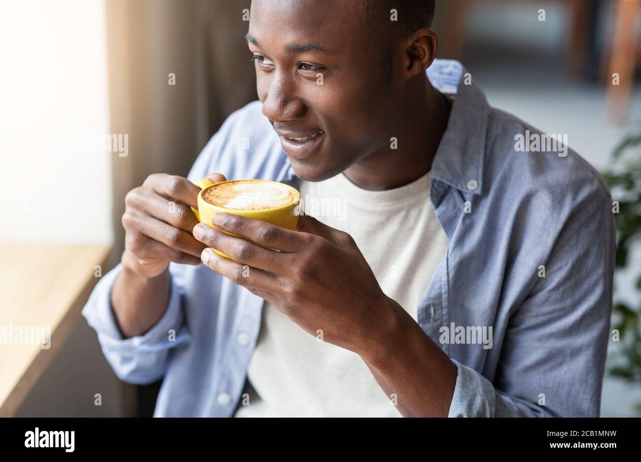 Young black man relaxing and drinking aromatic coffee in cafeteria ...