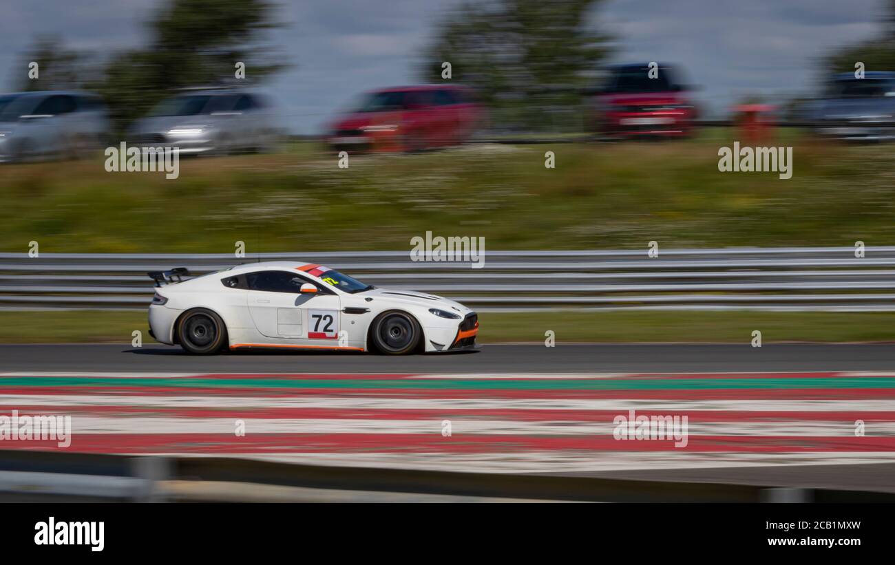 A panning shot of a white racing car as it circuits a track Stock Photo ...