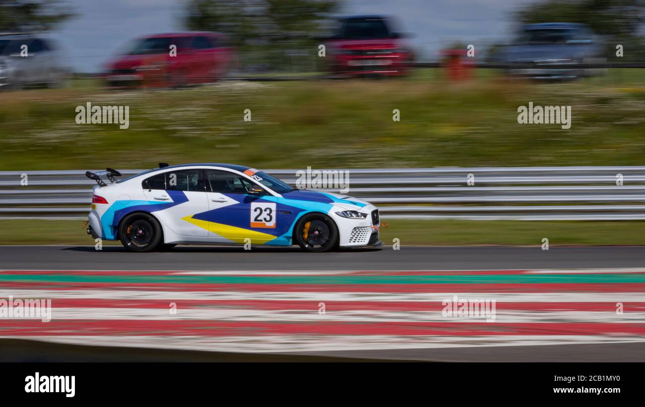 A panning shot of a blue and white racing car as it circuits a track ...