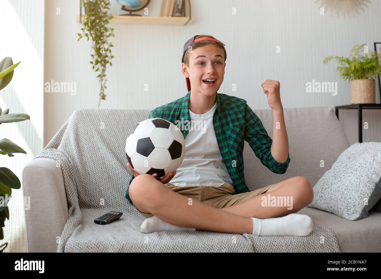 Excited teenager watching football match at home, celebrating win Stock ...