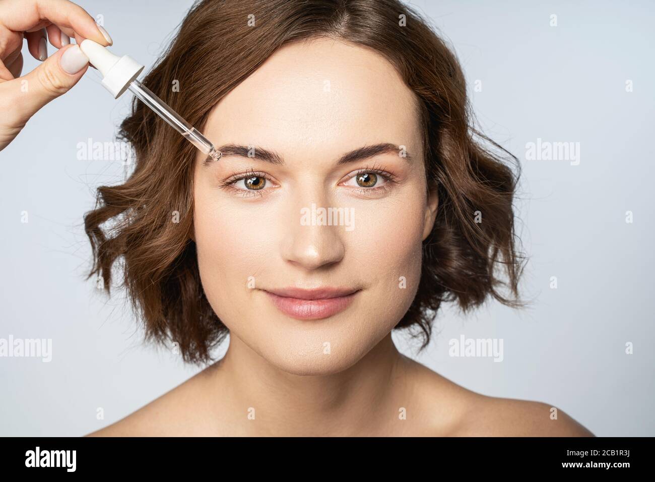 Female hand applying vitamin serum on lady face Stock Photo - Alamy