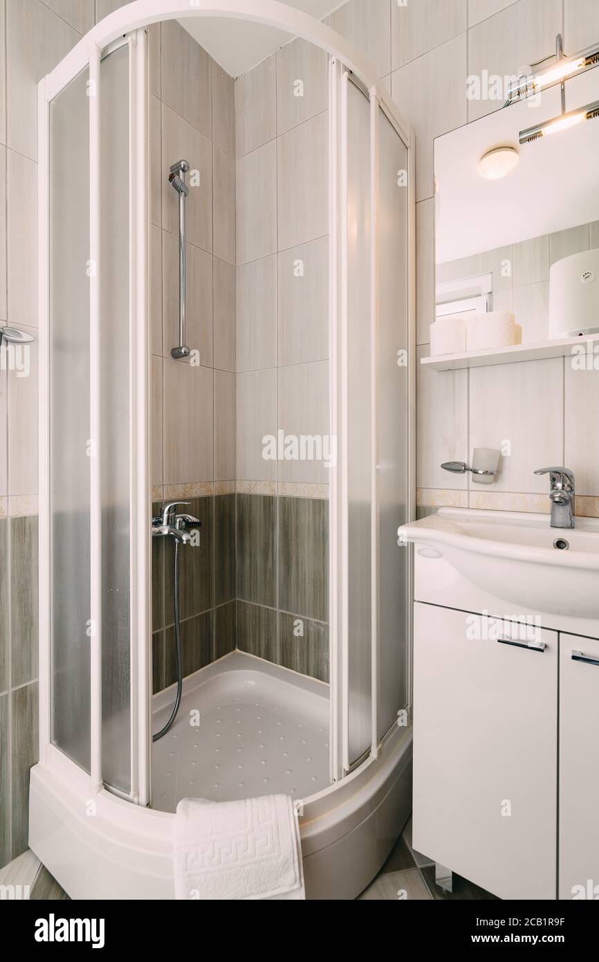 Open empty shower stall and washbasin in the bathroom with white tiles ...