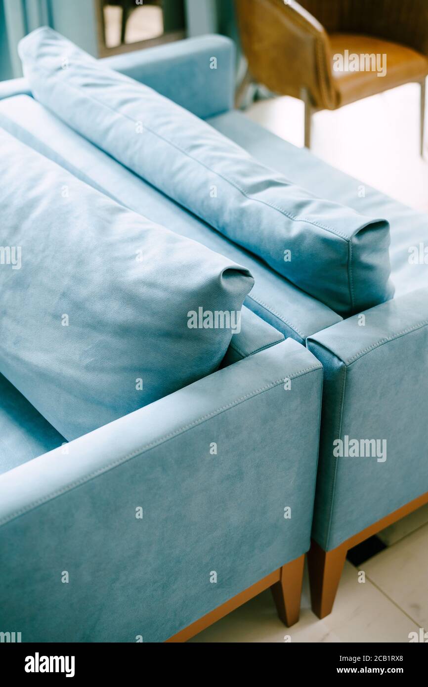 A close-up of two light blue sofas with pillows facing back to back ...
