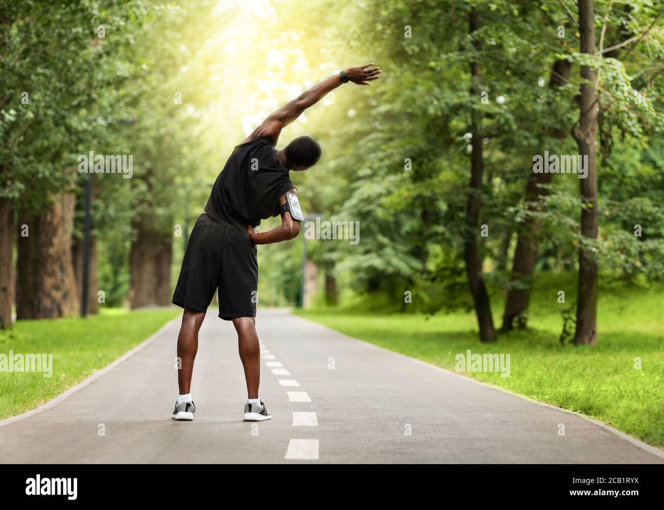 Muscular black guy stretching his body at park Stock Photo - Alamy