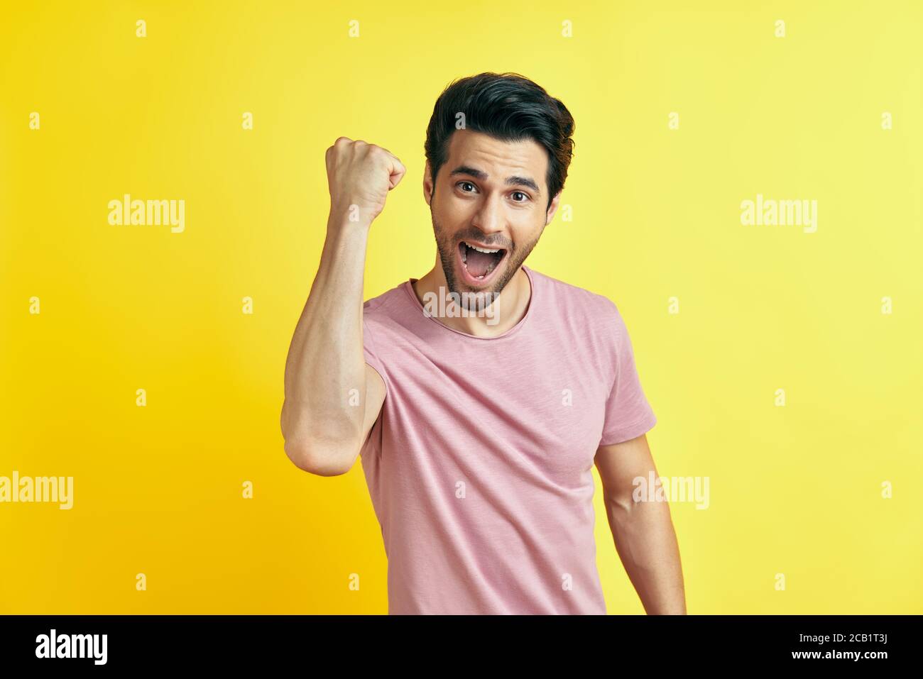 Happy man celebrating his success with winner gesture on yellow ...