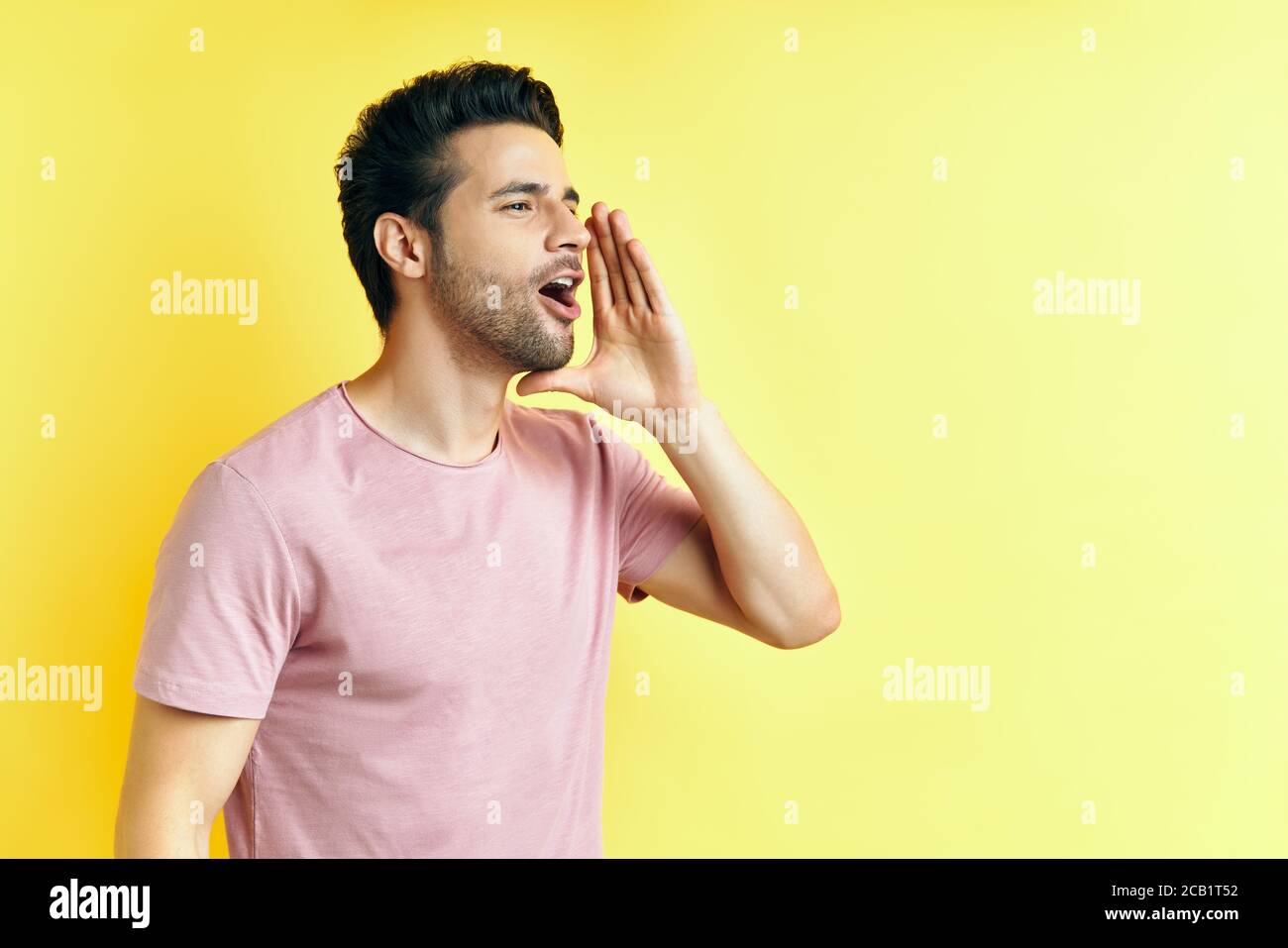 Young handsome man shouting and screaming loud to side with hand on ...