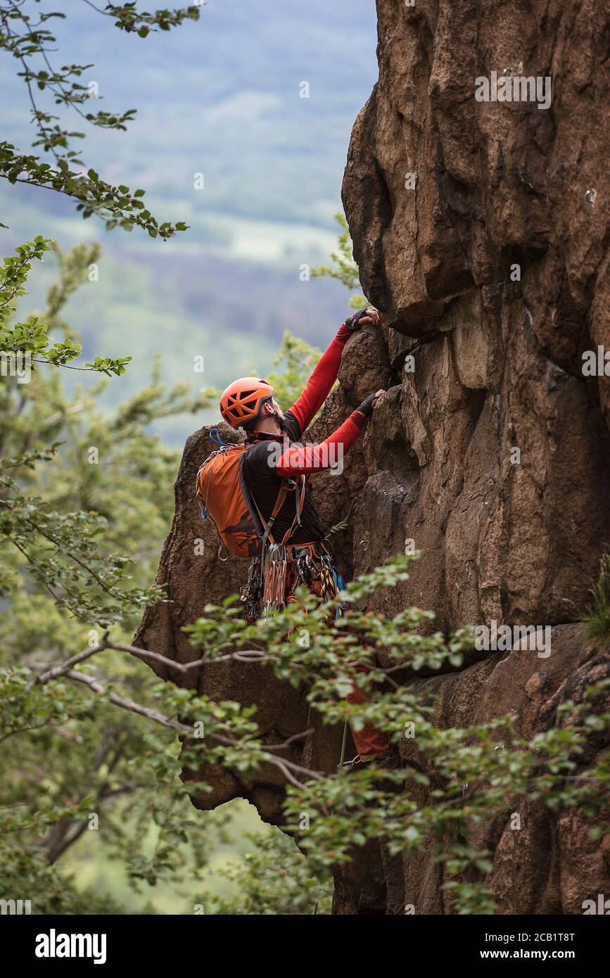 The climber with backpack climbing on the rock Stock Photo - Alamy