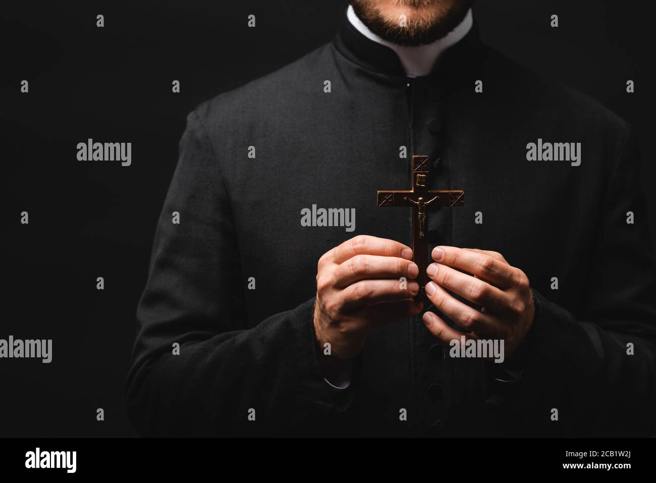 cropped view of pastor holding wooden cross isolated on black Stock ...