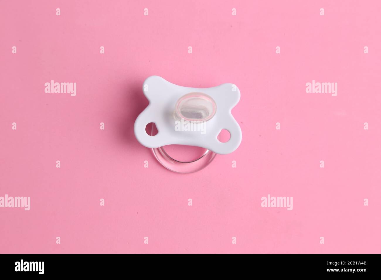 Overhead shot of a white pacifier on a pink background Stock Photo - Alamy