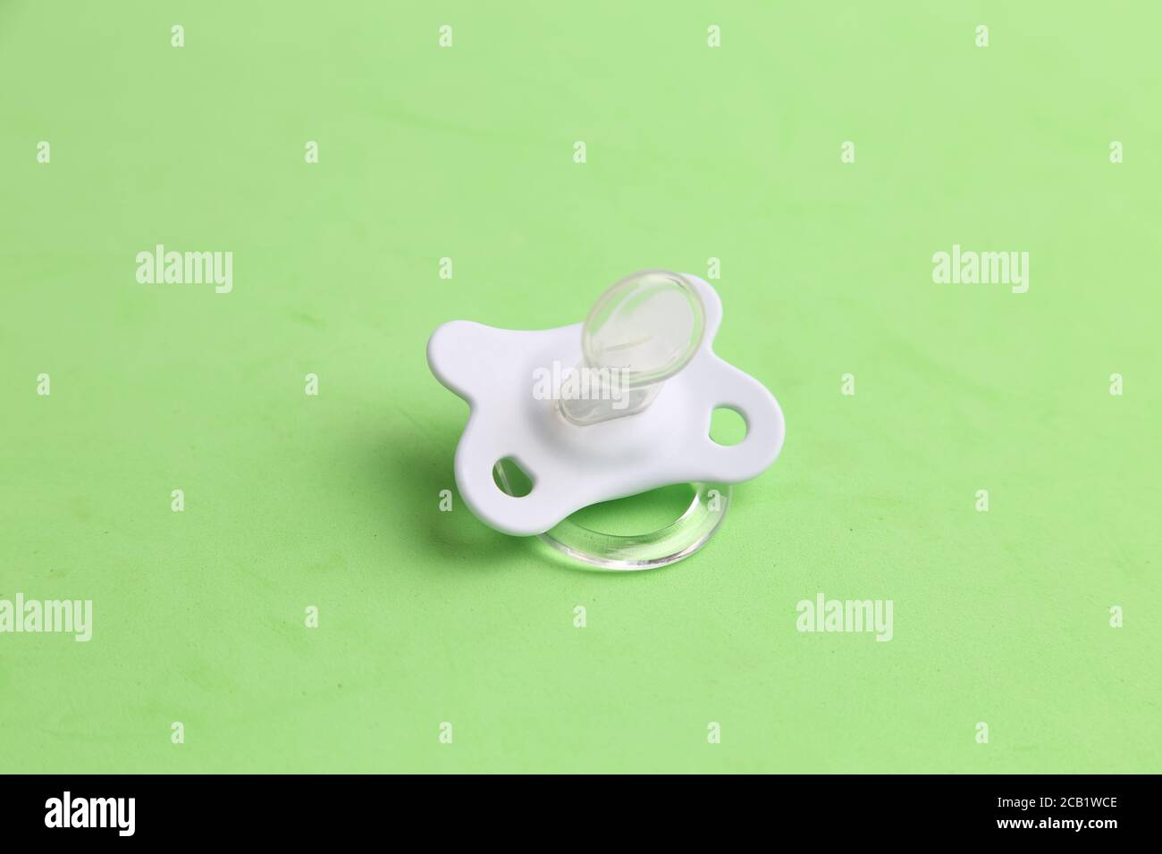 Closeup of a white pacifier isolated on a green background Stock Photo ...