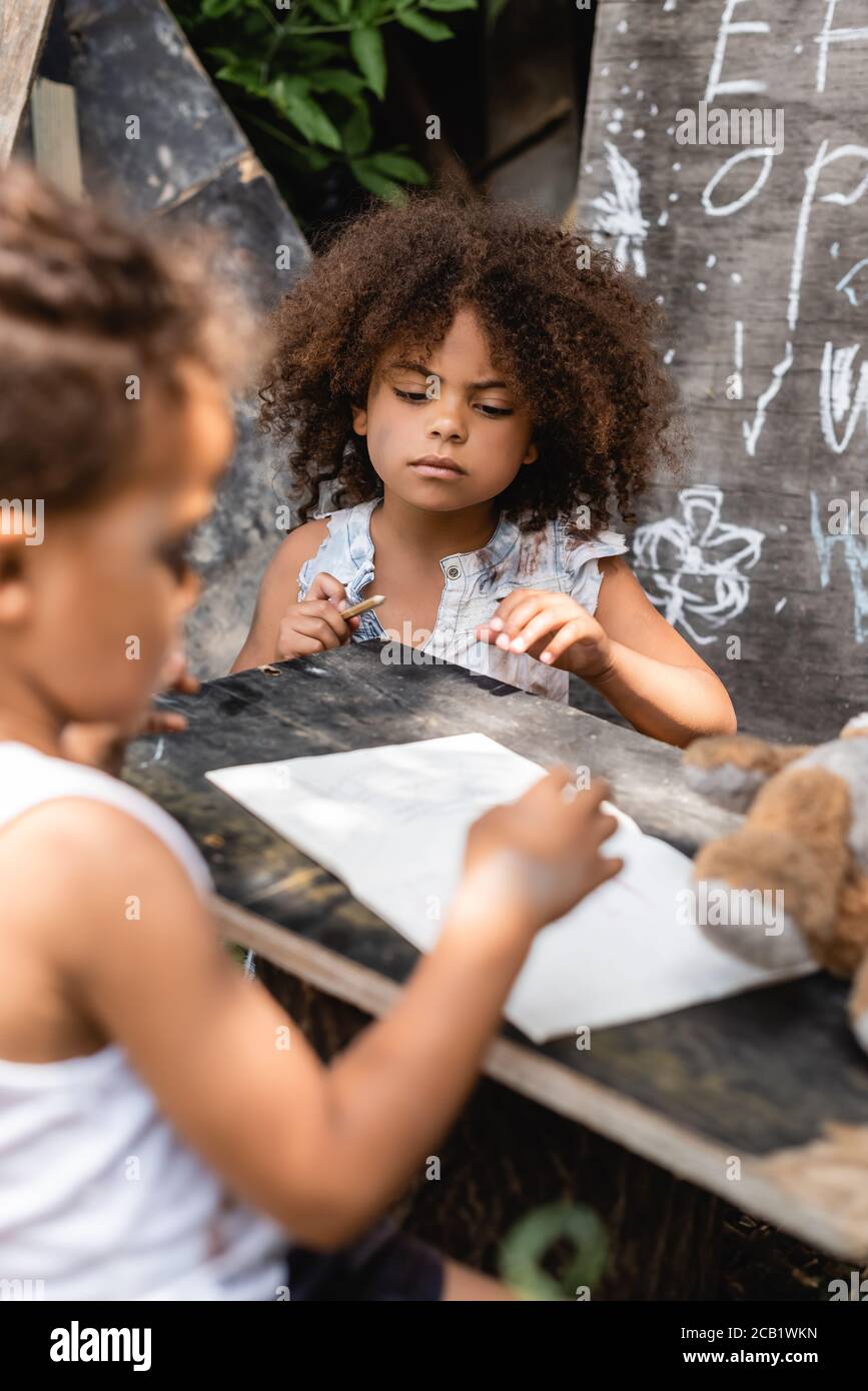 selective focus of poor african american kid looking at blank paper ...