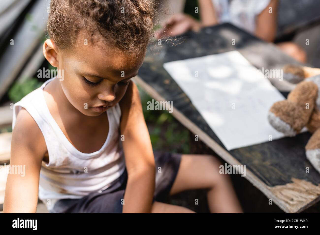 selective focus of poor african american boy looking down near table ...