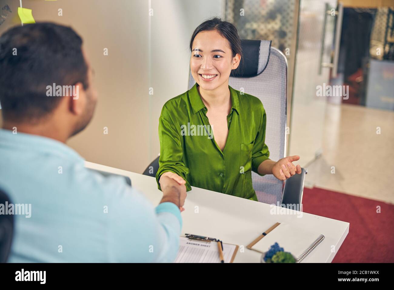 Positive delighted woman welcoming her new colleague Stock Photo - Alamy