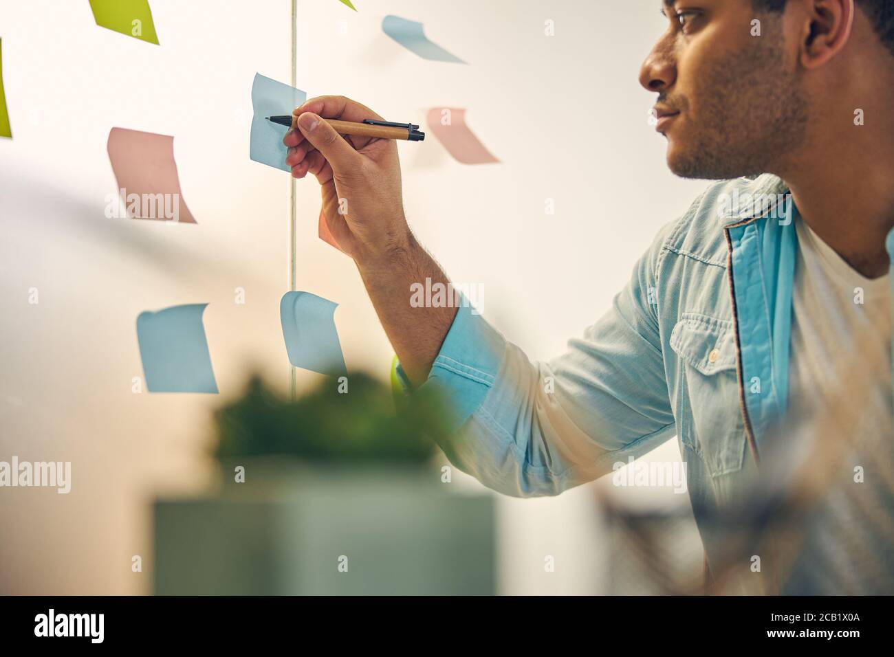 Handsome international man making notes on stickers Stock Photo - Alamy