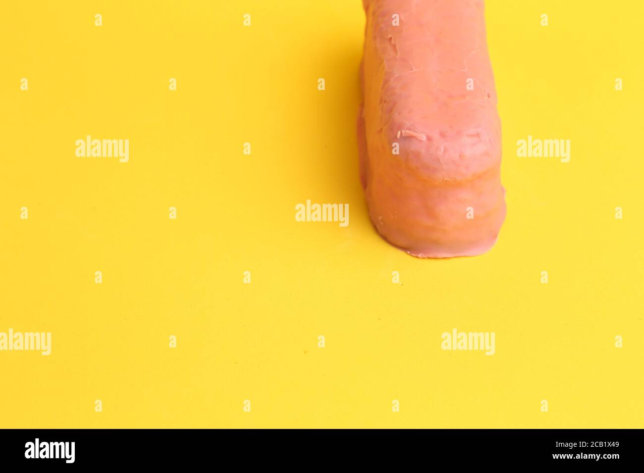 Top view of a long smooth pink pastry on a yellow background Stock ...